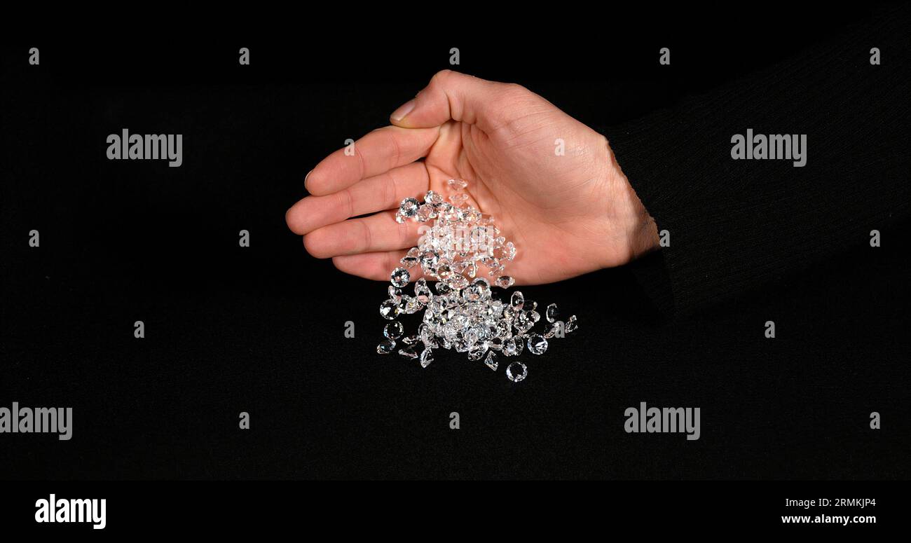Diamonds falling into Hand against Black Background Stock Photo - Alamy