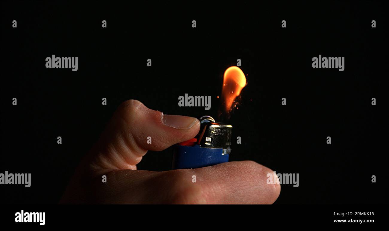 Lighter in Hand with Flame against Black background Stock Photo - Alamy