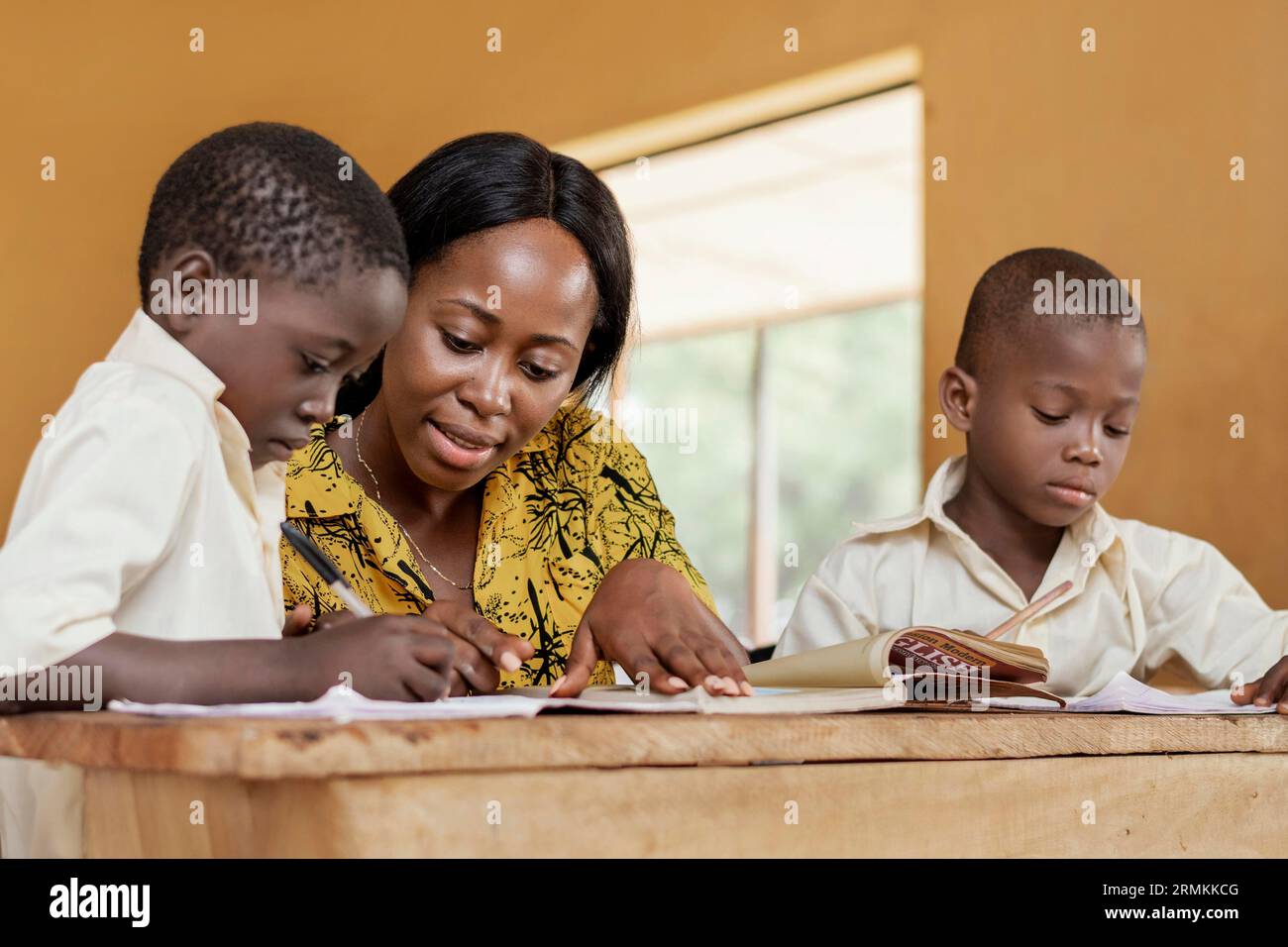 Teacher helping kids class Stock Photo - Alamy