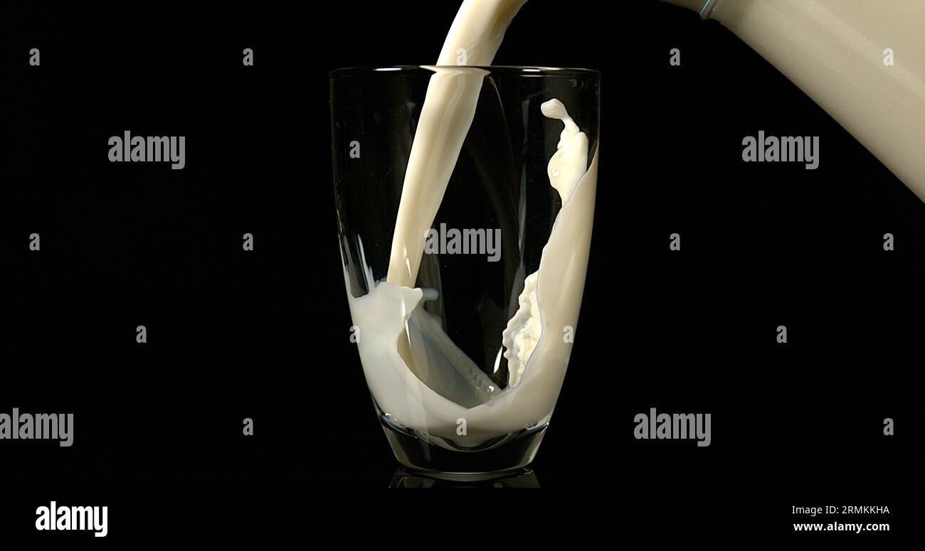 Milk being poured into Glass against black Background Stock Photo - Alamy
