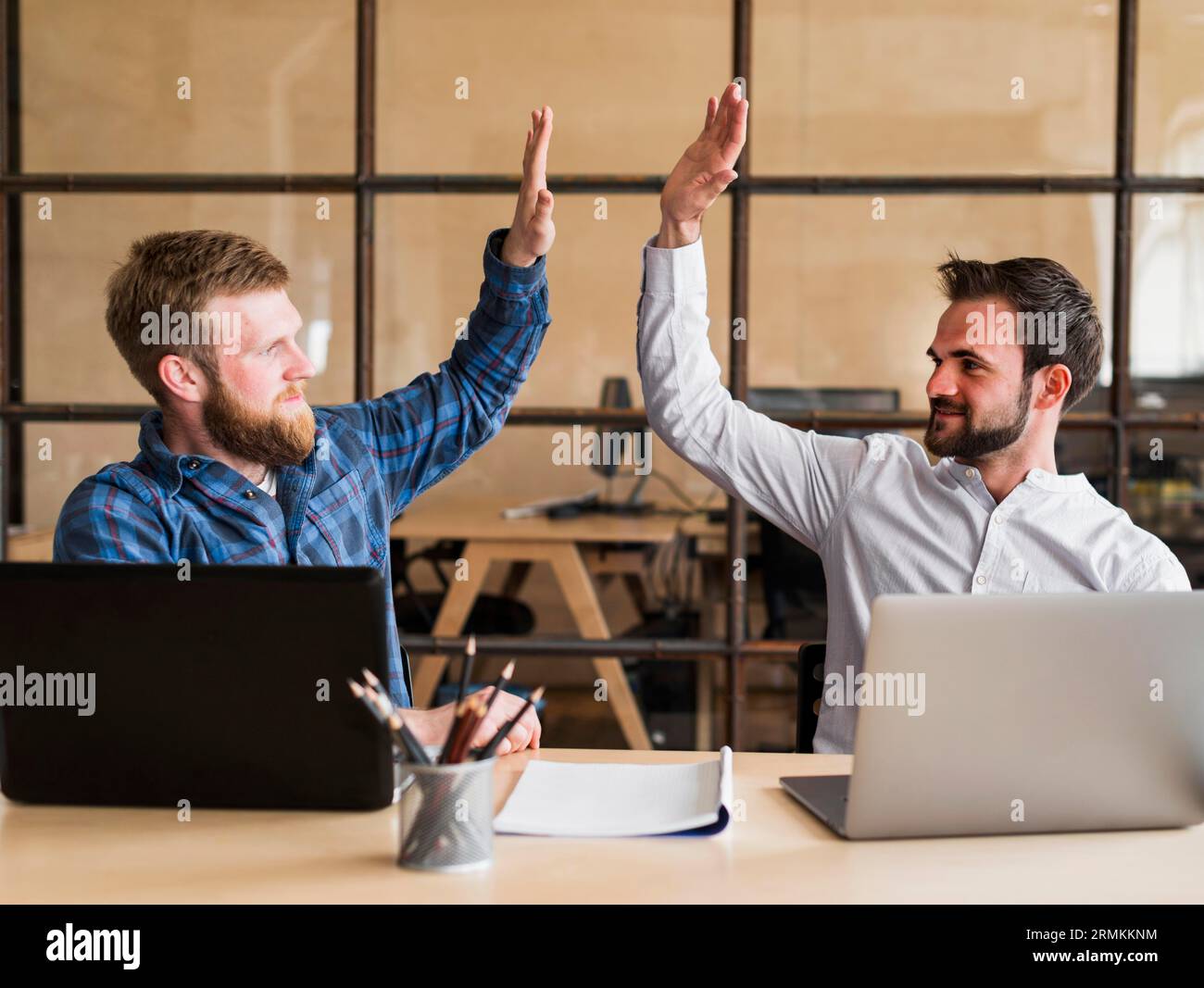 Two successful male colleague giving high five office Stock Photo - Alamy