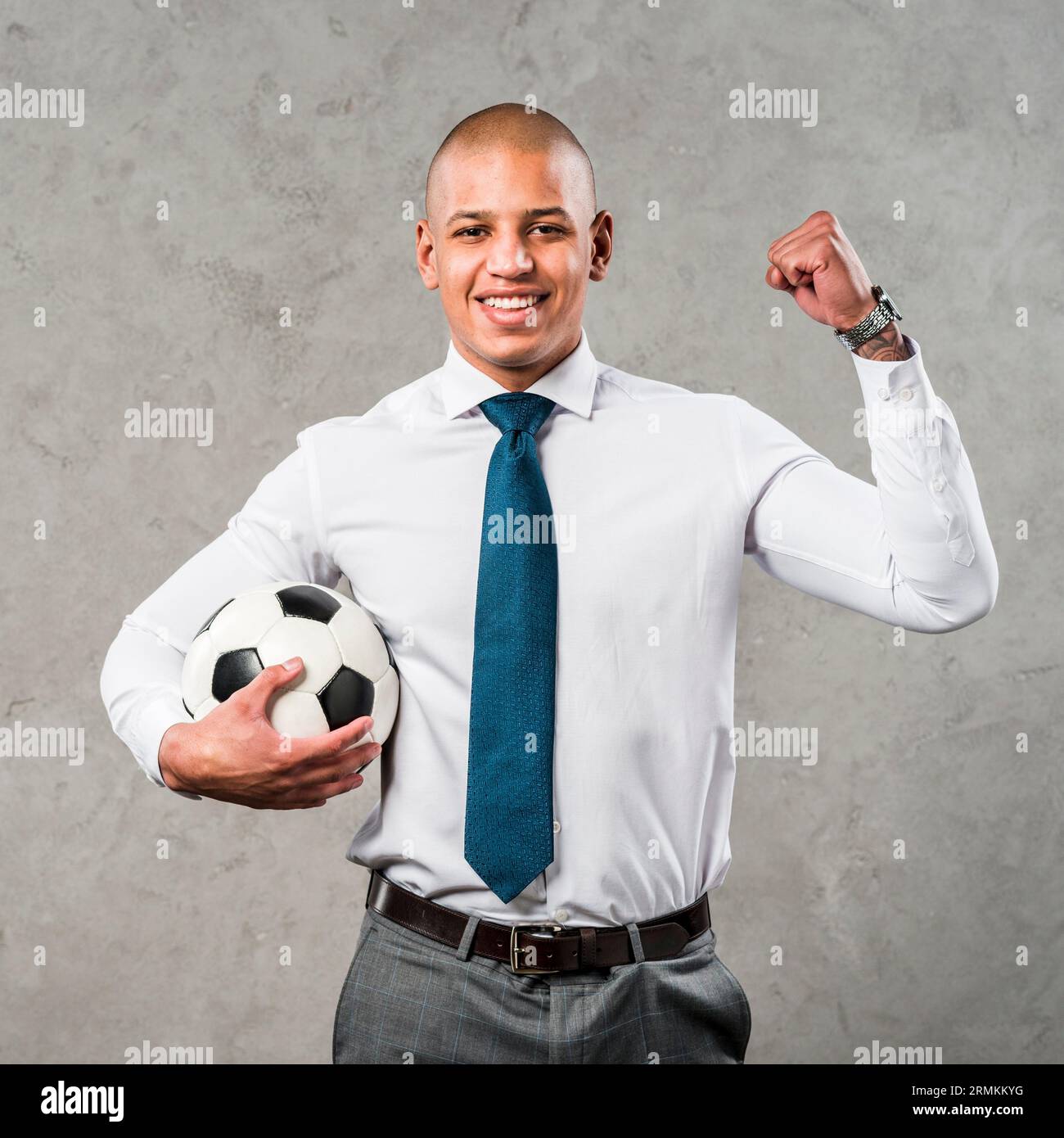 Young businessman holding soccer ball hand clenching her fist standing ...
