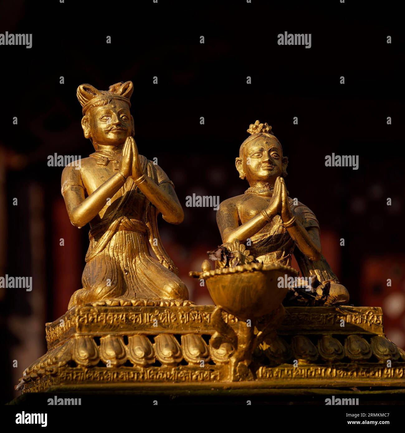 Golden statues of a man and a woman sitting and praying in the morning ...