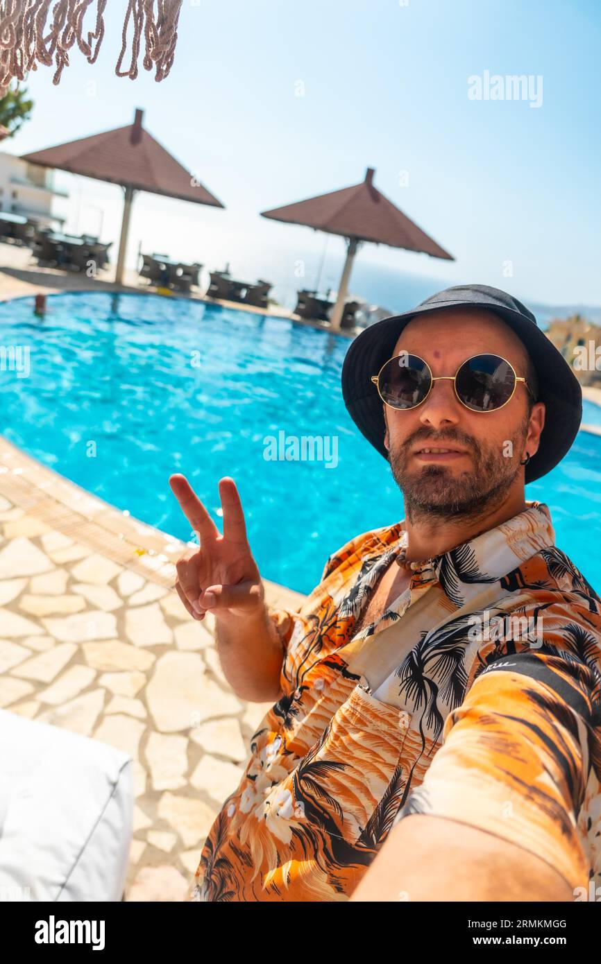 Tourist Man In The Hotel Pool In Summer Taking A Selfie Enjoying The
