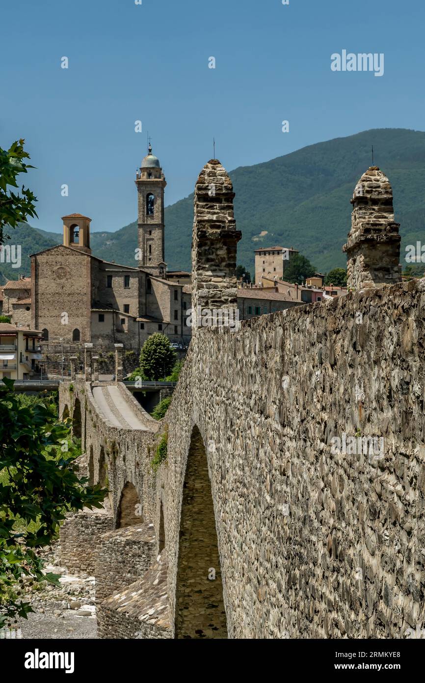 A detail of the ancient stone bridge of Bobbio, Italy, with the town in ...