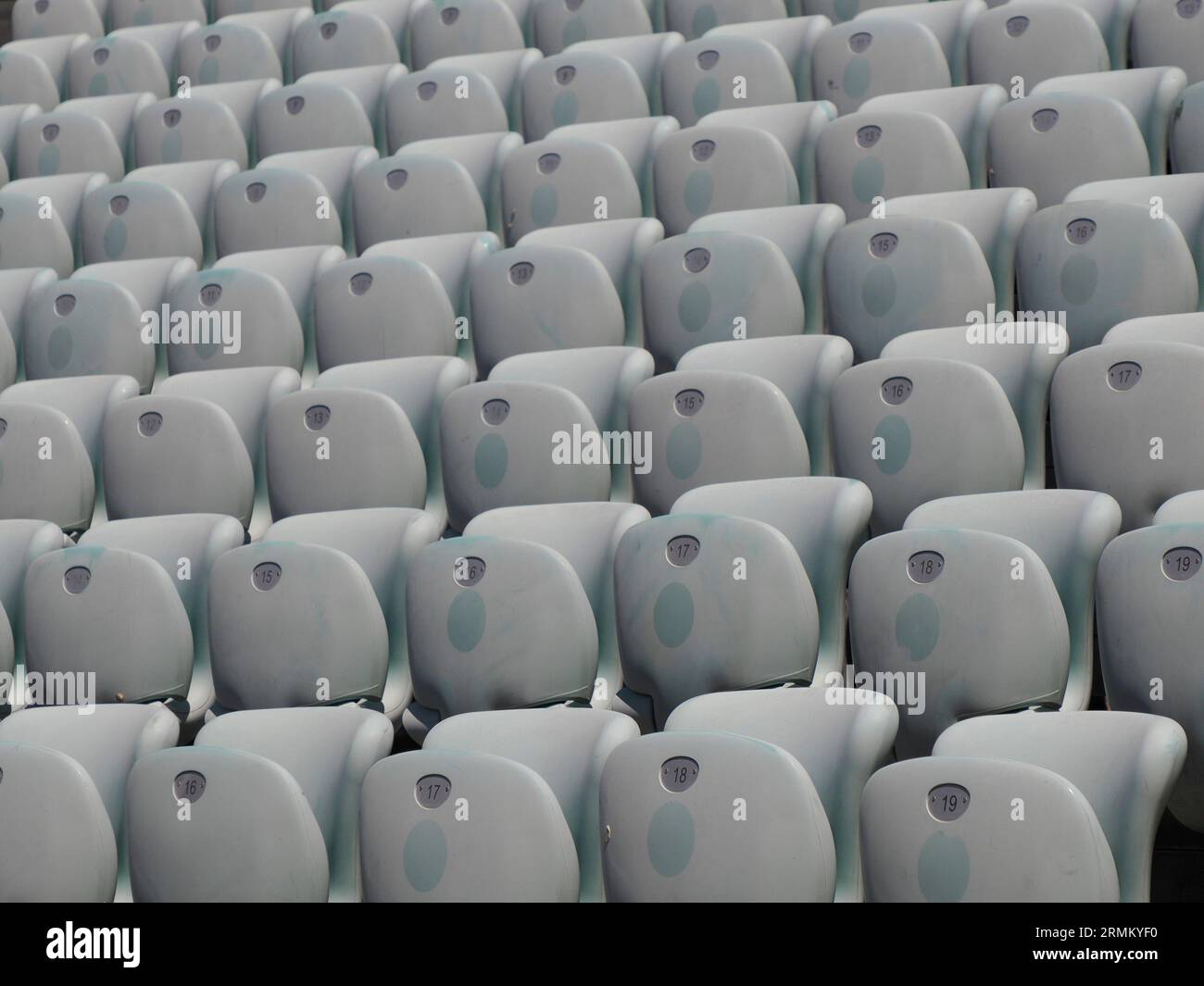 Rows of numbered empty plastic seats at an open-air amphitheater many ...