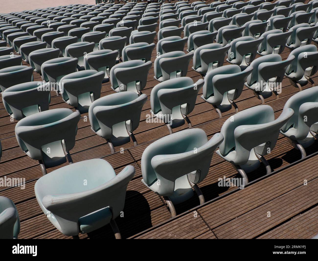 Rows of numbered empty plastic seats at an open-air amphitheater many ...