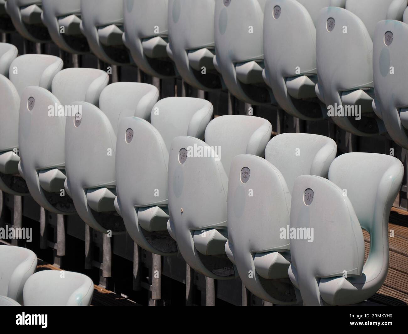 Rows of numbered empty plastic seats at an open-air amphitheater many ...