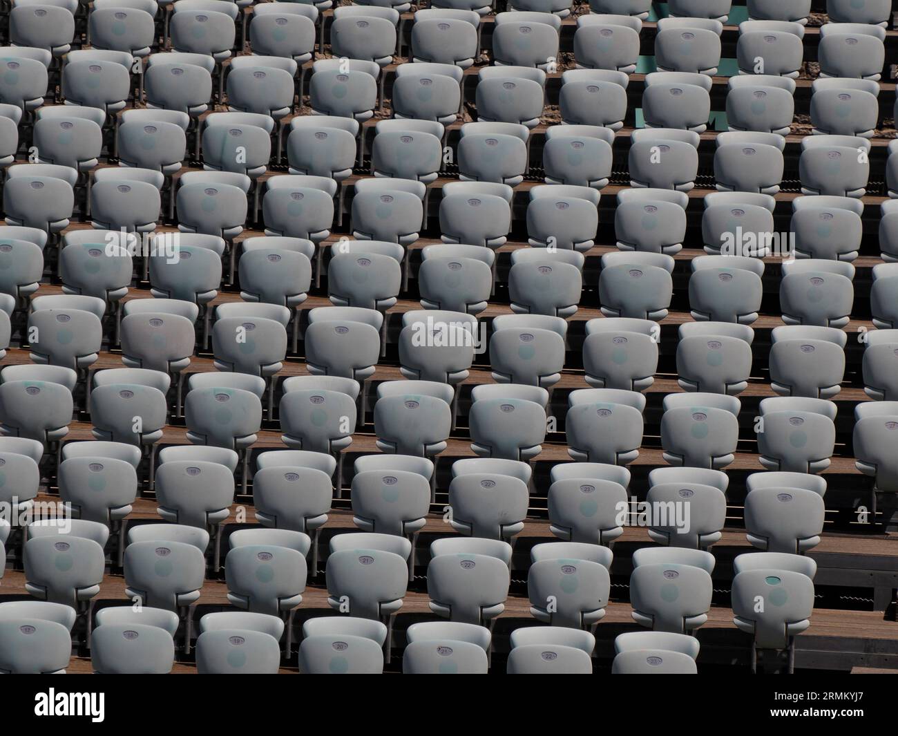 Rows of numbered empty plastic seats at an open-air amphitheater many ...