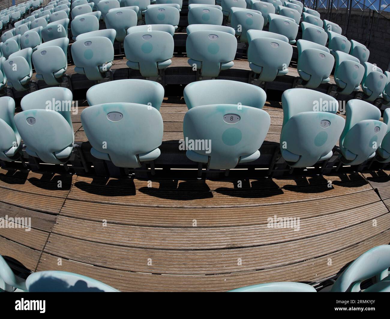 Rows of numbered empty plastic seats at an open-air amphitheater many ...