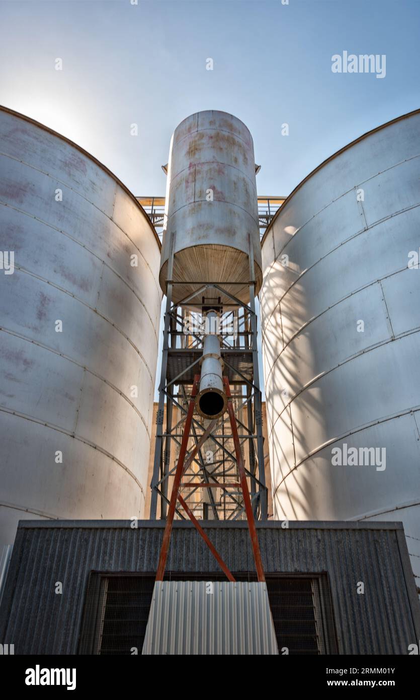 Looking up to two silos with a railway feeder between, blue sky with a ...