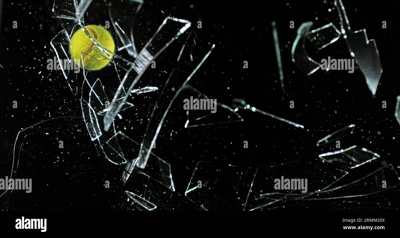 Tennis Ball breaking Pane of Glass against Black Background Stock Photo ...