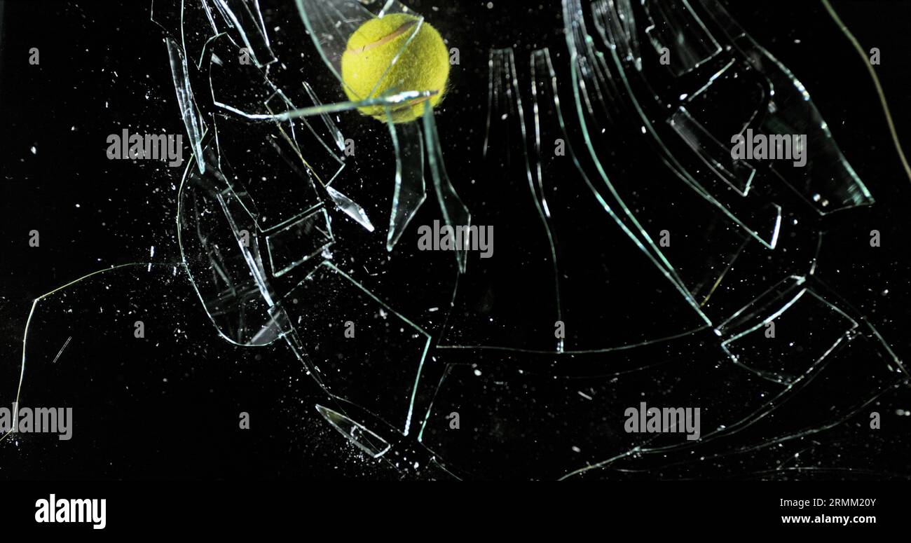Tennis Ball breaking Pane of Glass against Black Background Stock Photo ...