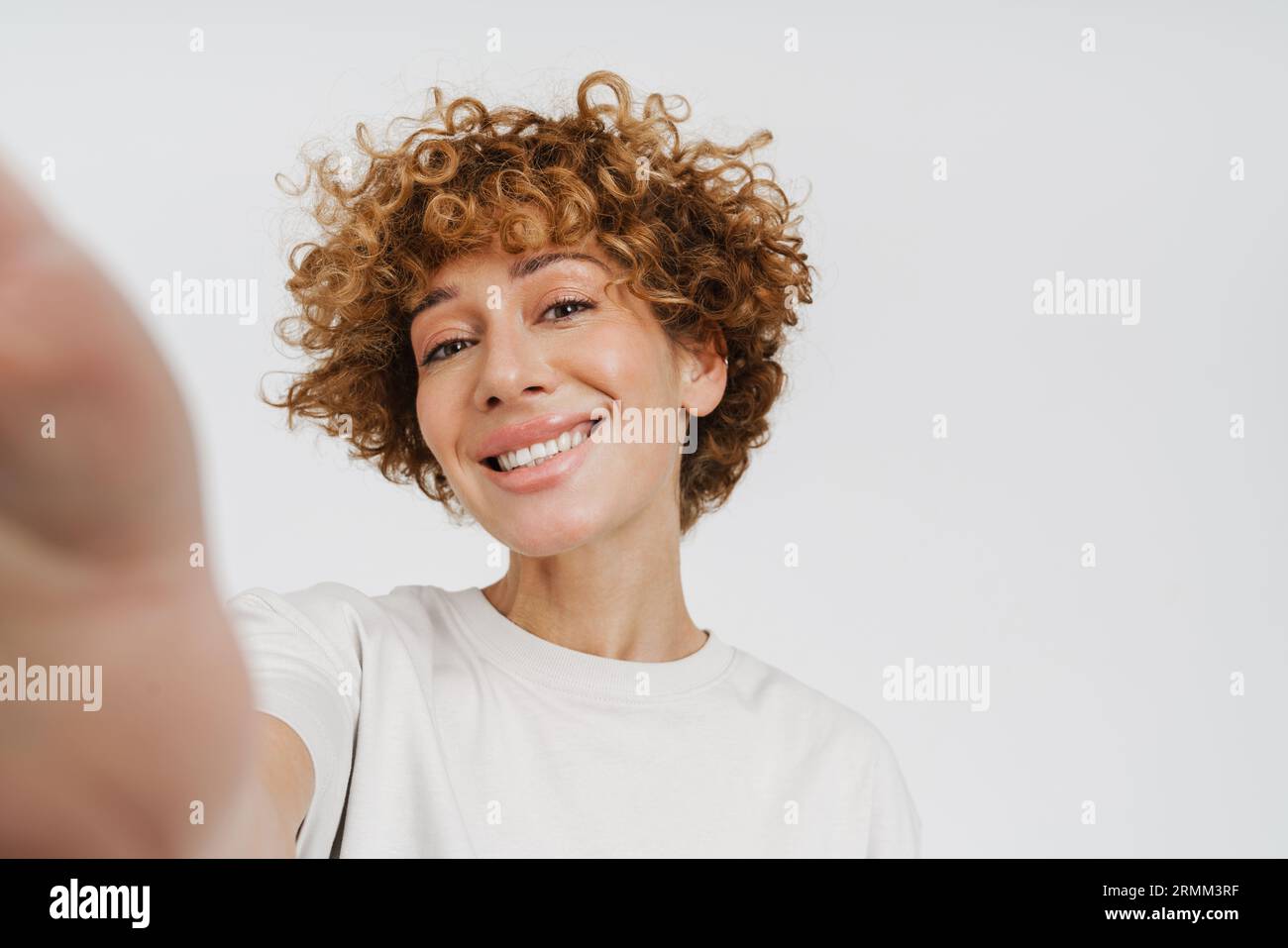 Middle-aged smiling ginger woman taking selfie isolated over white ...