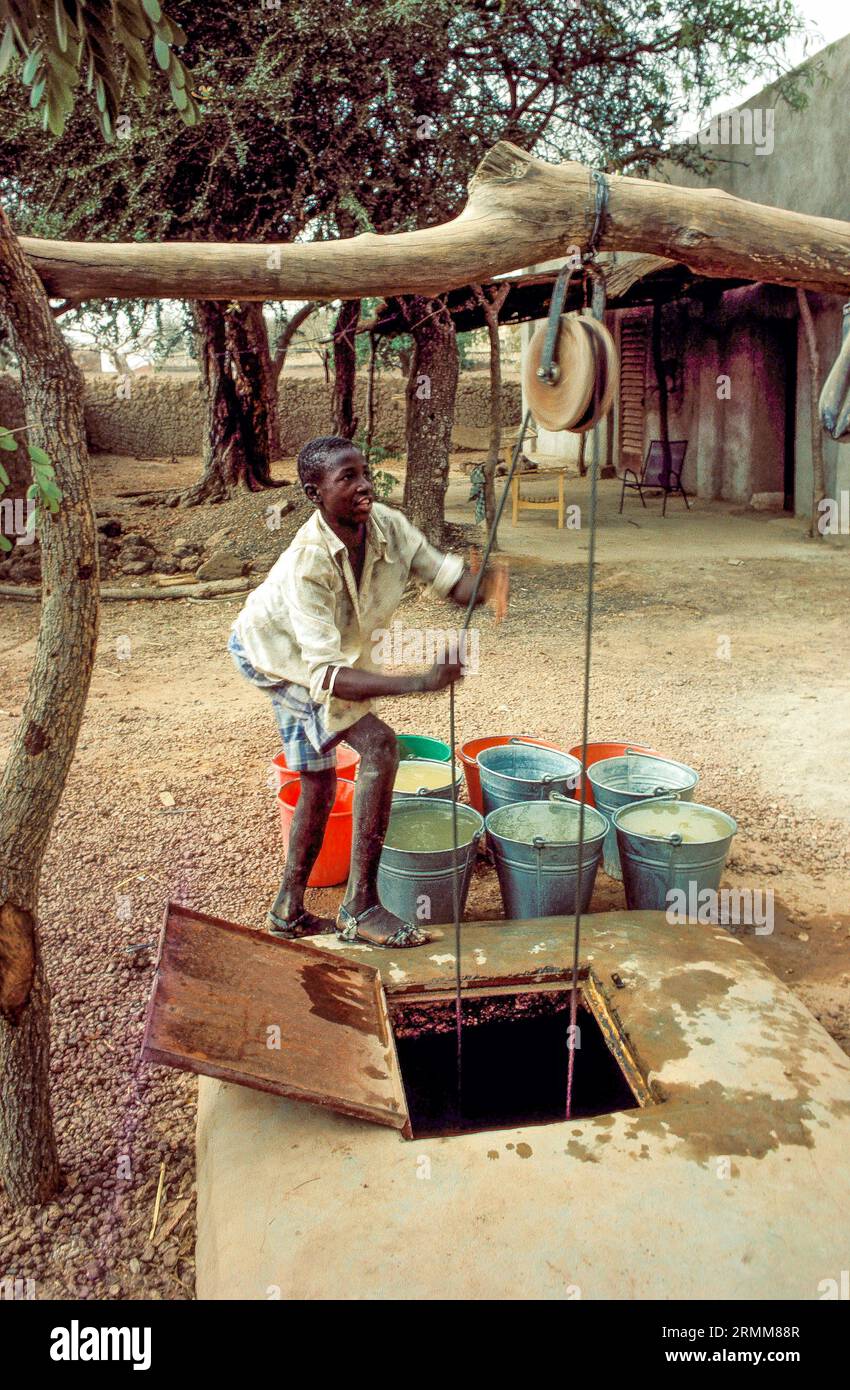 Mali - Boy fetches water from a village well with the help of a pulley ...