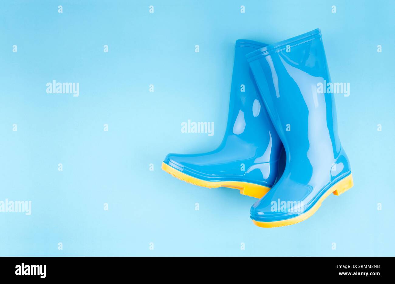 A Pair of blue rubber boots on light blue background, top view with ...