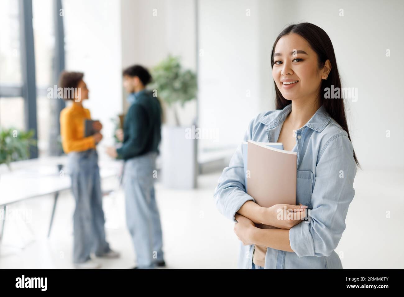 Happy asian student lady holding workbooks and smiling at camera ...