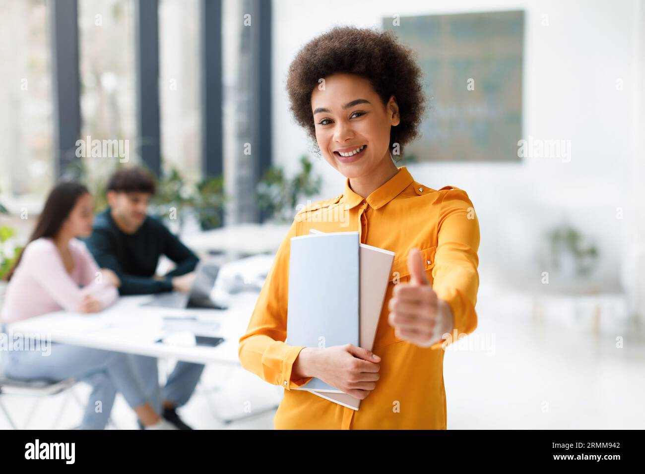 Portrait of happy black lady student showing thumb up, standing in ...