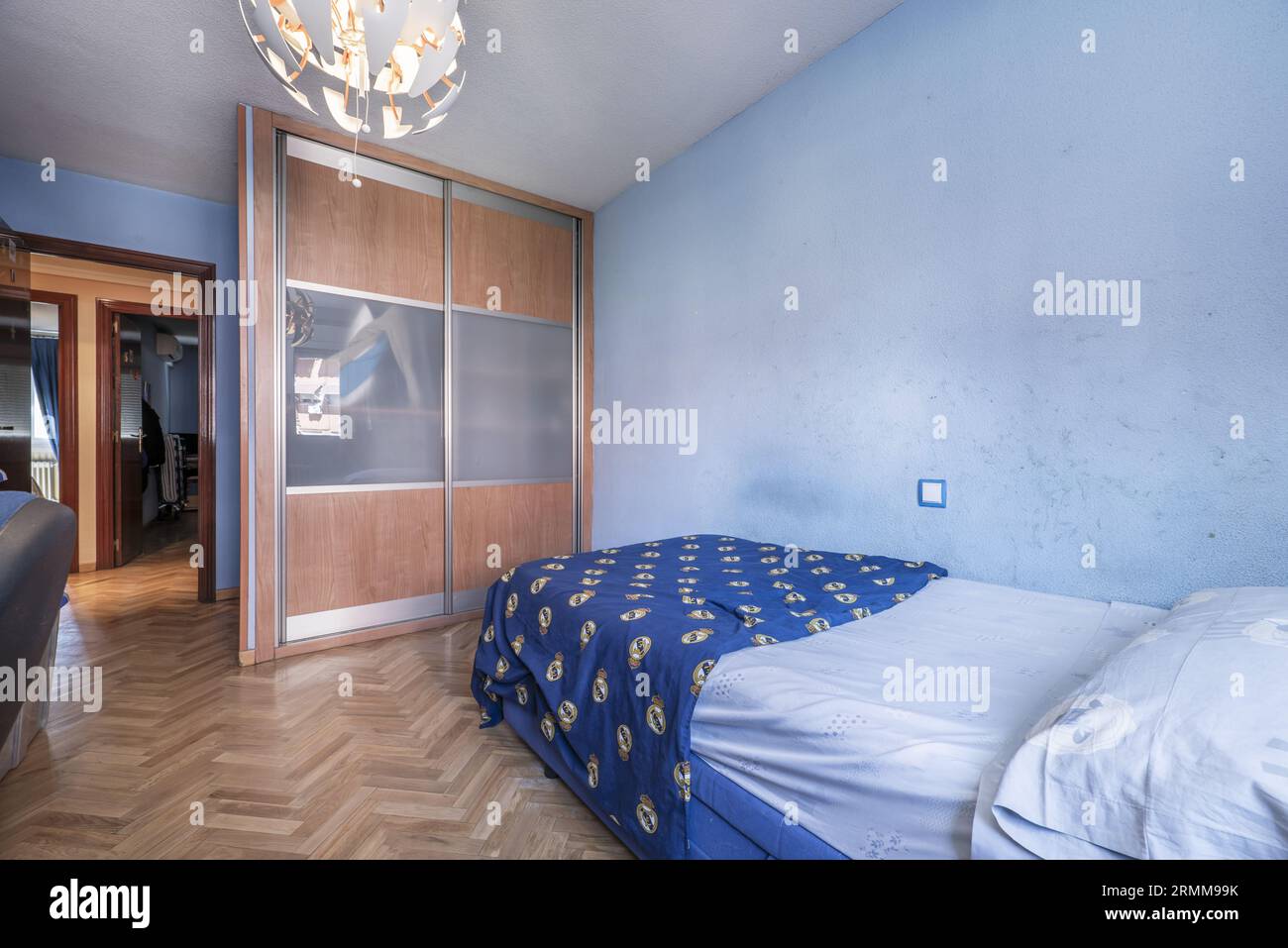 A bedroom with a single bed with a blue tail, a built-in wardrobe with ...