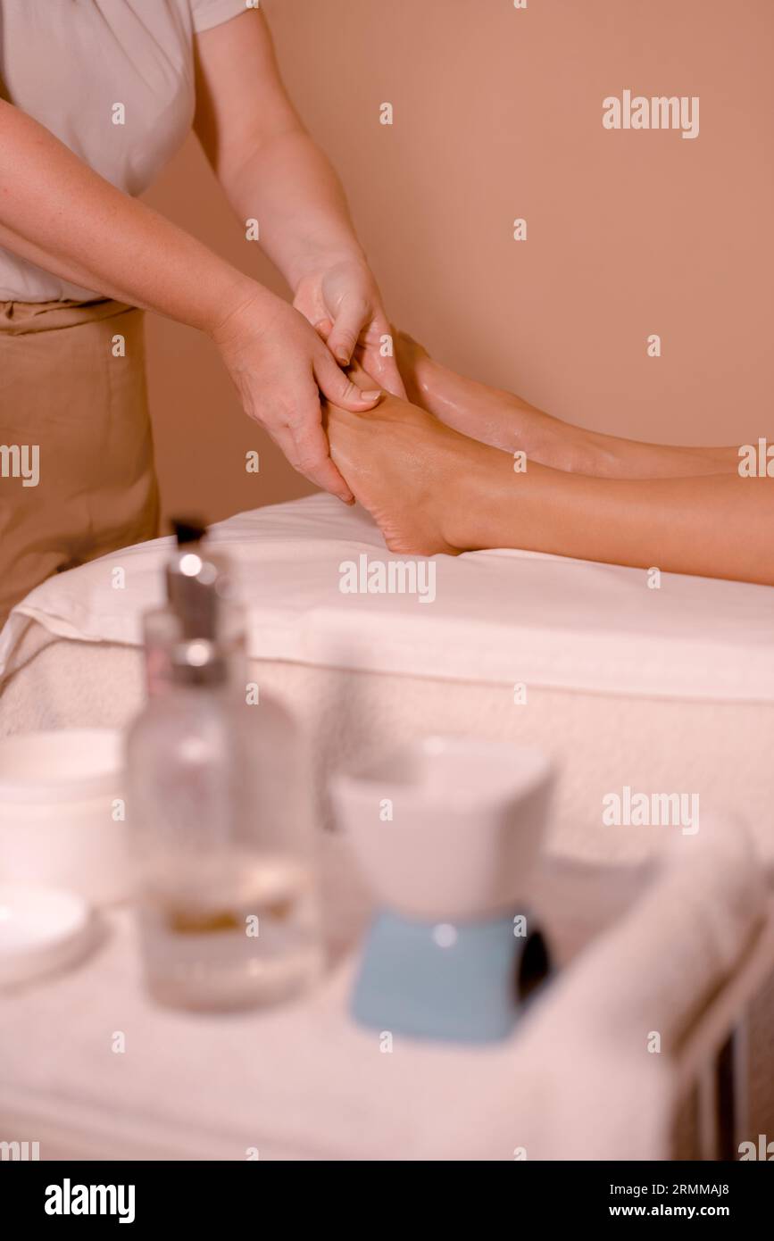 Experienced masseuse giving her woman client relaxing Thai foot massage ...