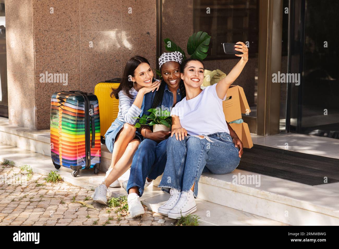 Cheerful multiethnic ladies helping their girlfriend moving to new ...