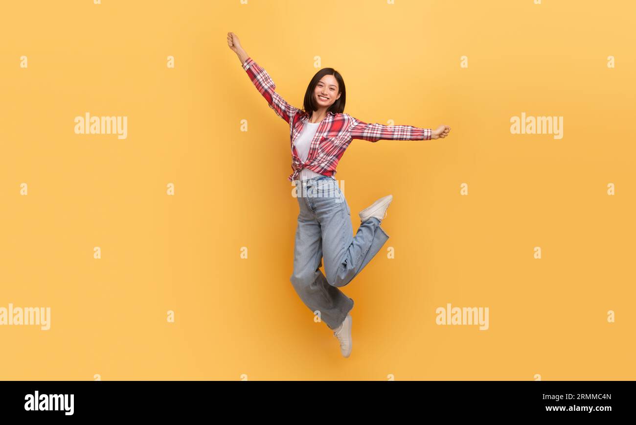 Carefree asian lady jumping in air and smiling, happy japanese woman ...