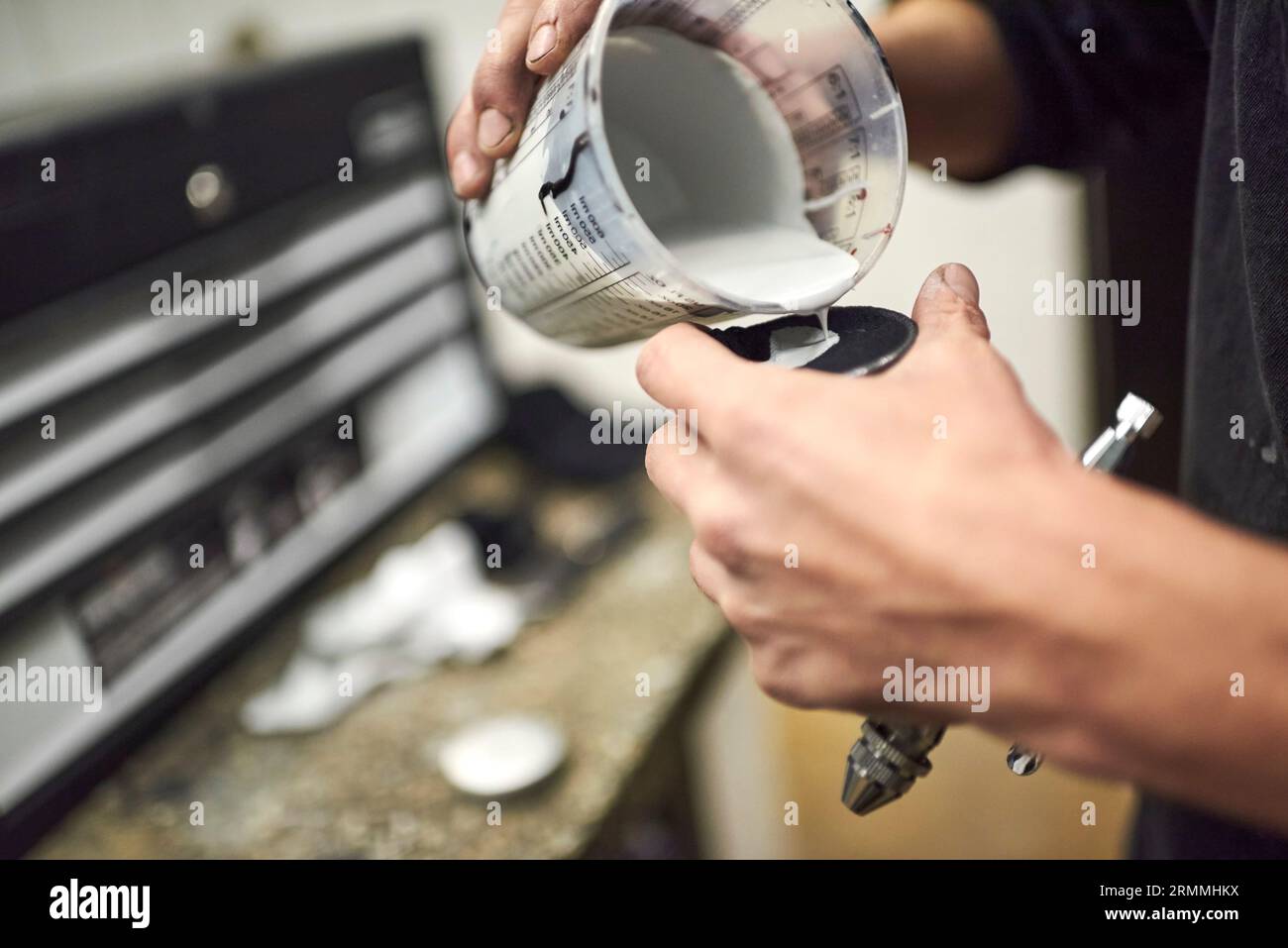 Hands of a young unrecognizable man pouring paint into a spray paint ...