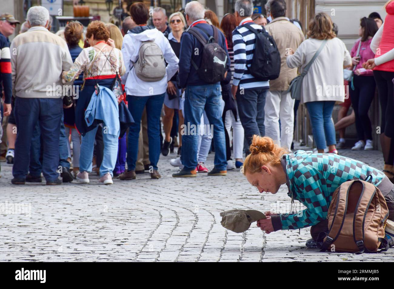 Young red haired women on her knees in the streets of Prague. She is ...