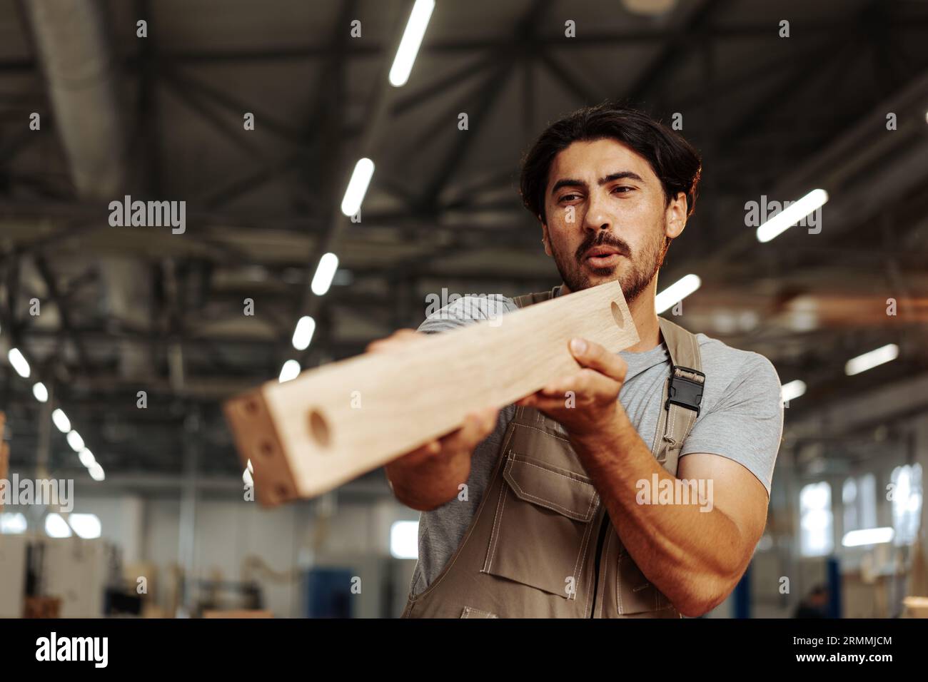 Young carpenter man looking and choosing wood plank at workshop in ...