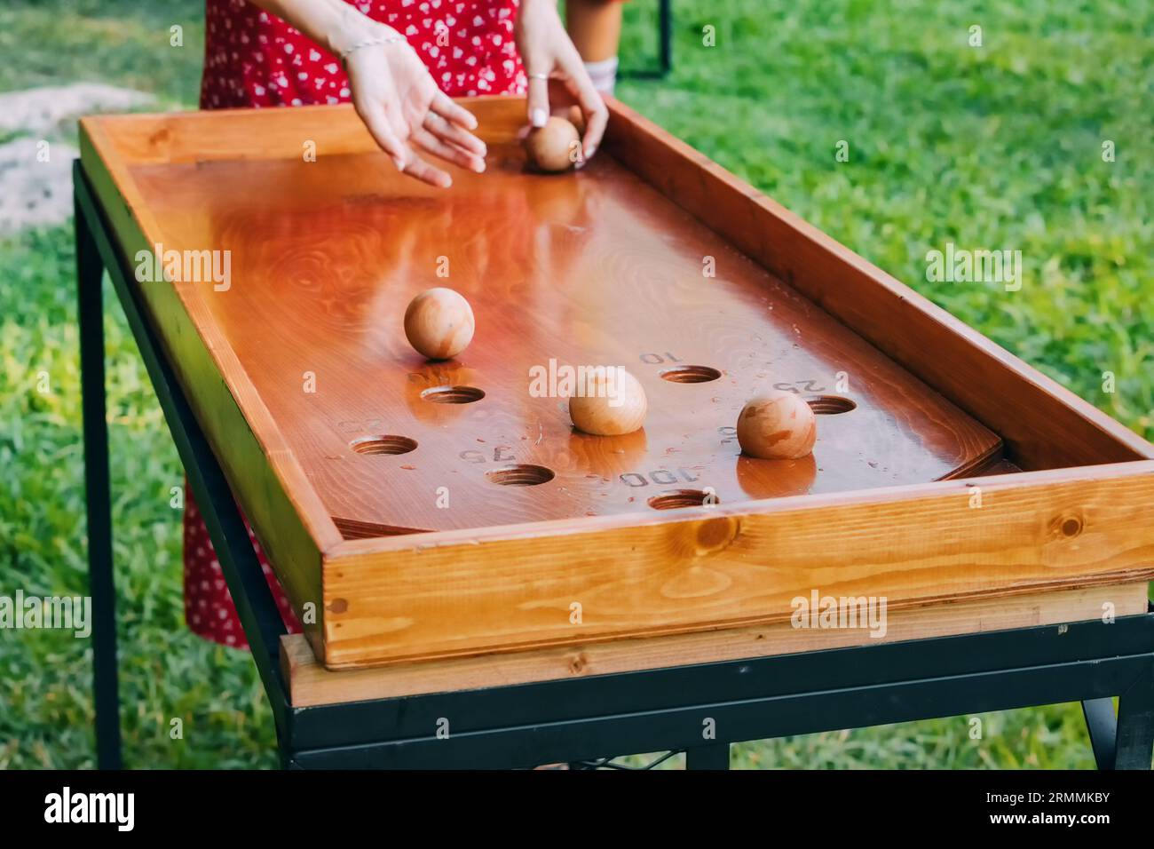 Wooden Pastimes: Amidst a summer backdrop, hands engage in a fun board ...
