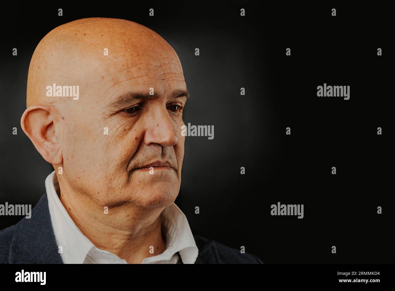 Depicted beside vast COPYSPACE, a bald, dignified elder in blue ponders ...