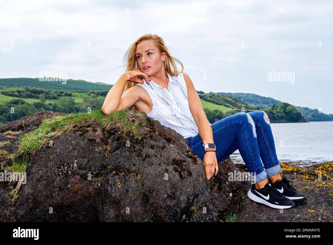 Woman seated on rocky beach hi-res stock photography and images - Alamy