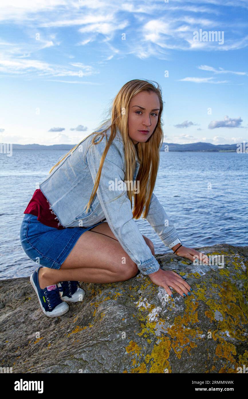 A beautiful blonde woman, Rhianna Martin, sits on the rocks at Wormit ...