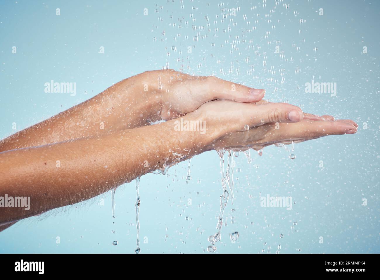 Cleaning, hands and water splash on woman in studio, blue background ...