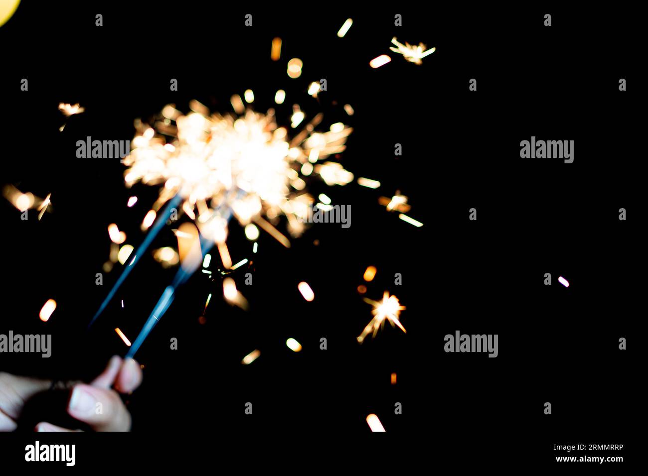 Hand holding a burning sparkler against fireworks background Stock ...