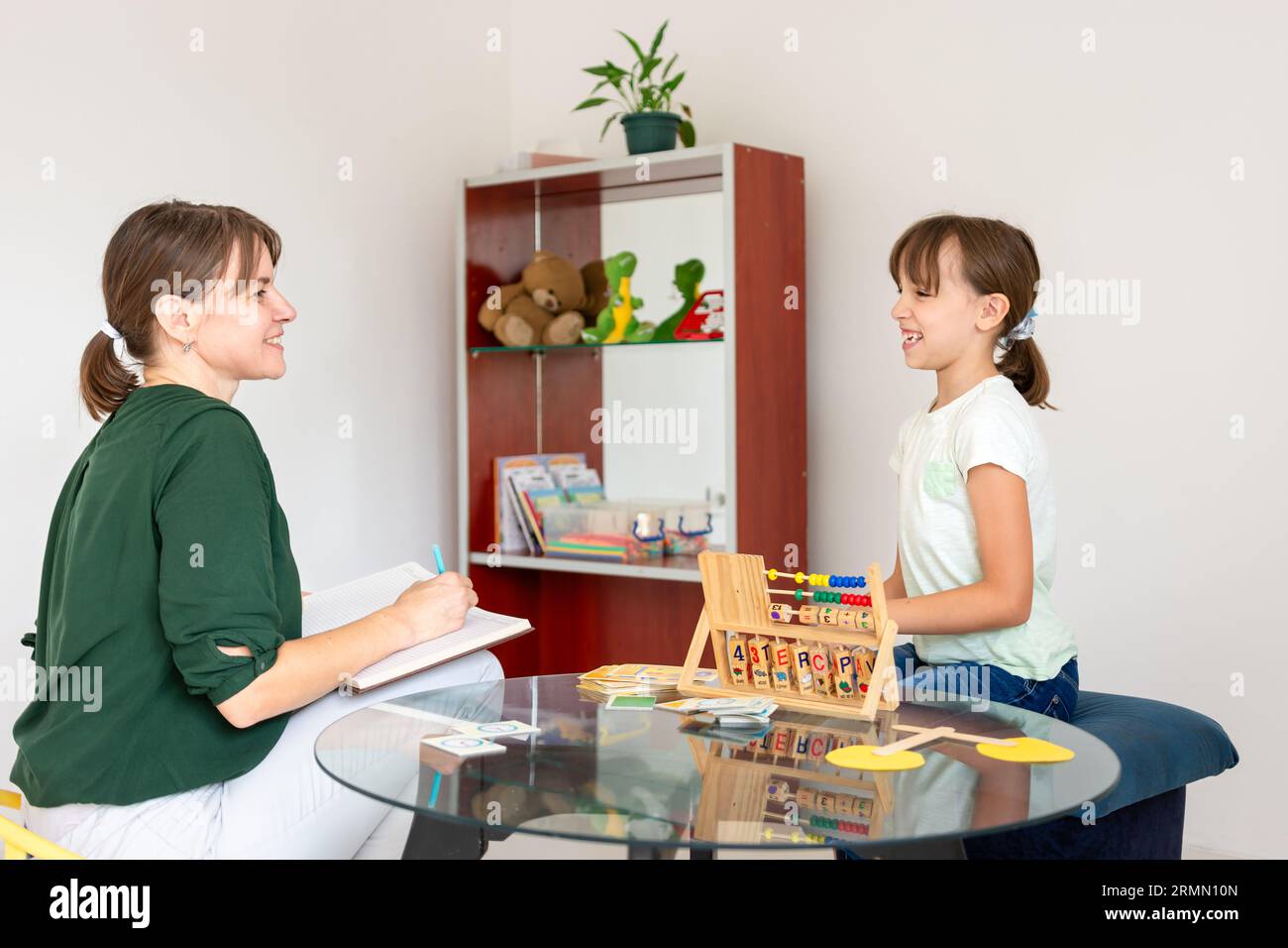 Female child psychologist working with a little elementary girl in a ...