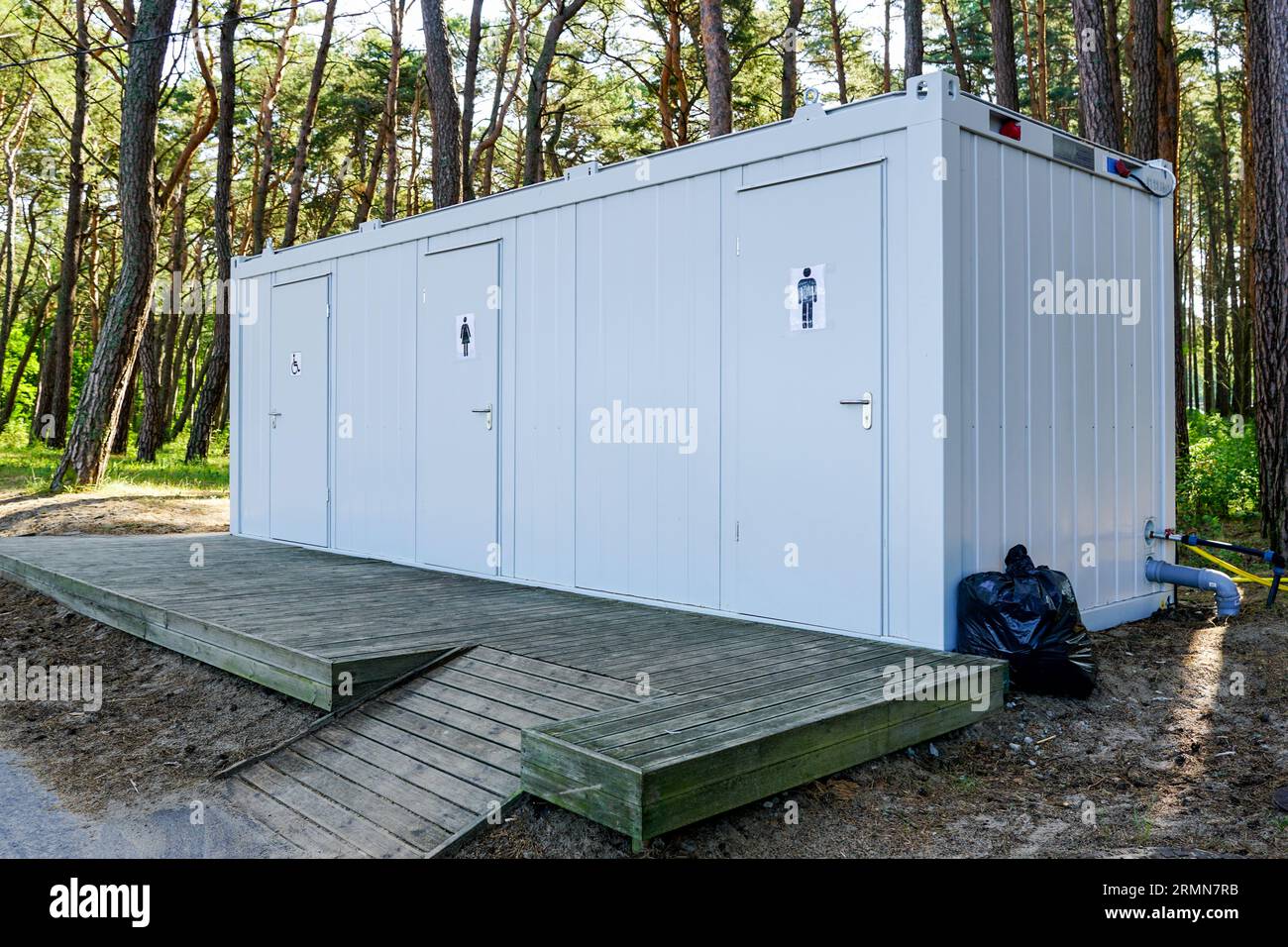 Modern public metal three toilet container with a wooden terrace in a ...
