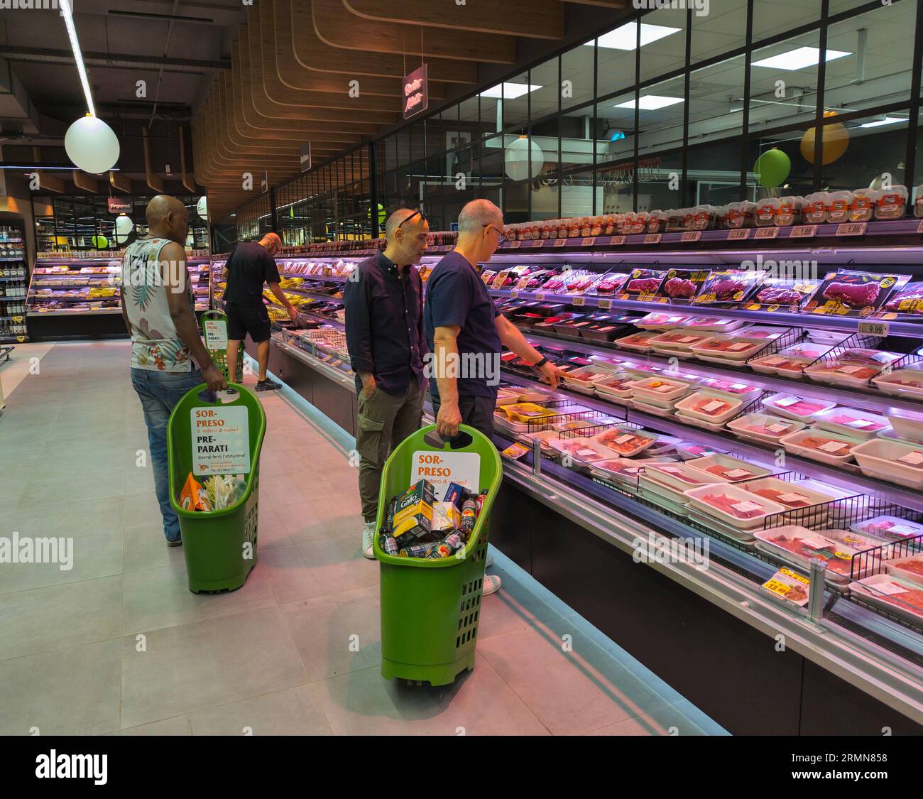 Men compare the prices of meat, in the butcher section of a large ...