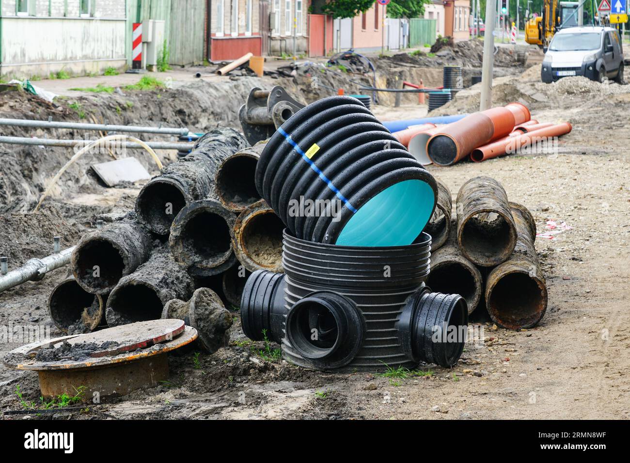 Street reconstruction view, old and new underground pipes next to a deep wide trench, pipe ...