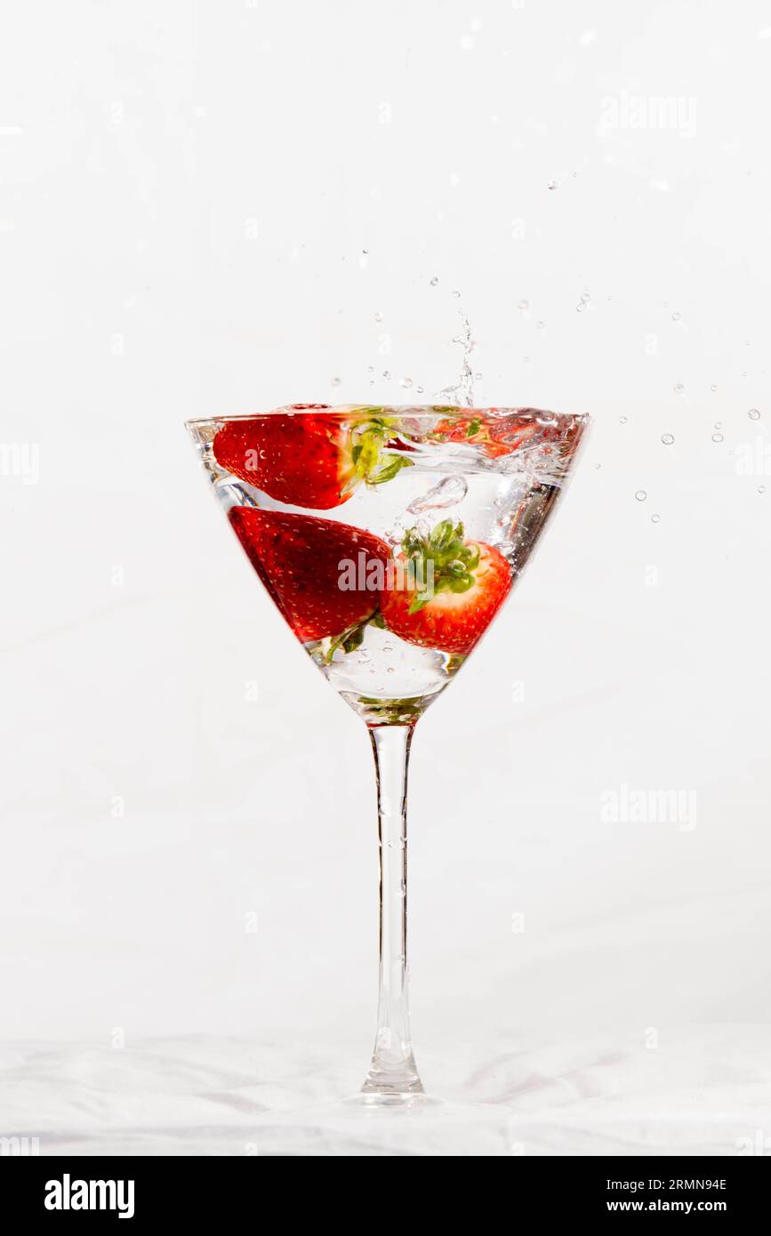 A glass of alcoholic beverage with ripe strawberries floating in it ...