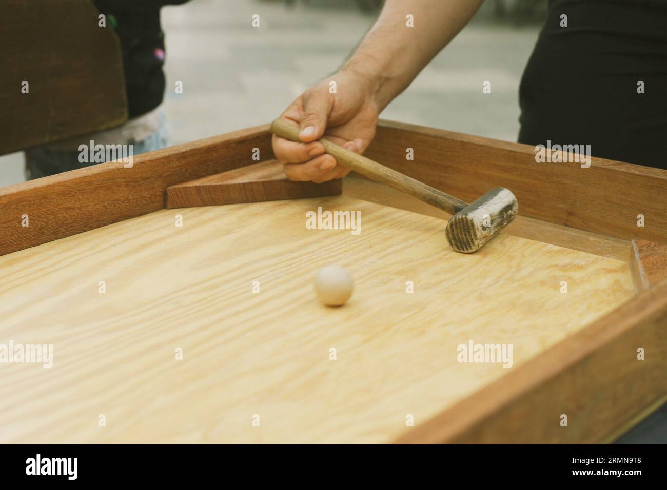 Adults play a wooden board game with a ball and a bat. Close-up Stock ...