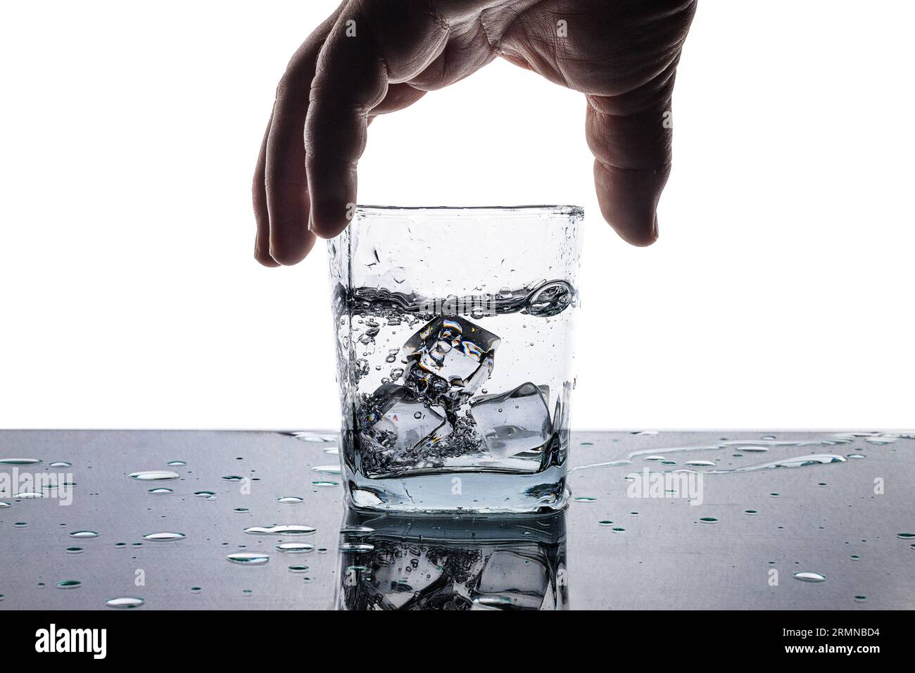 Hand grabbing a glass of ice water. Light background. Reflection of ...