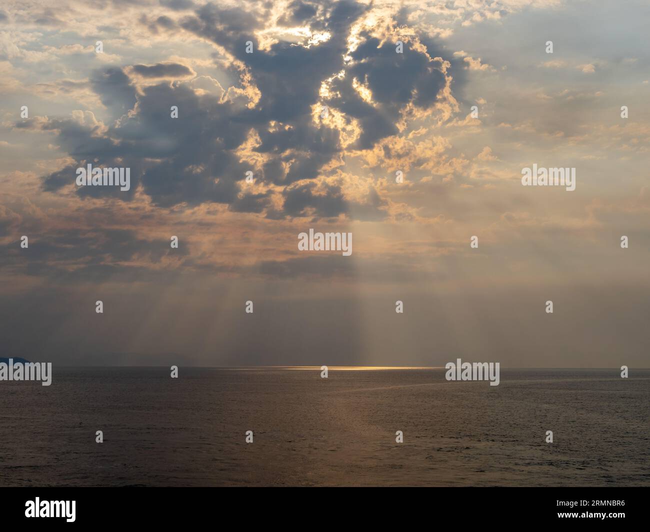 Sunbeam through the haze. Dramatic sky with glowing clouds and sea near ...