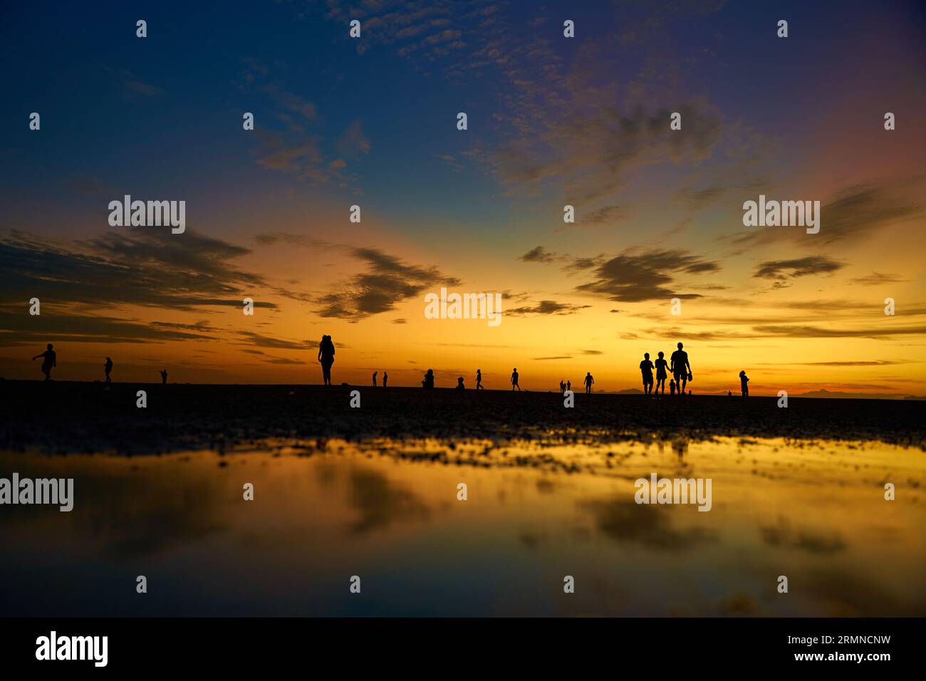 Silhouettes of people walking on the ocean floor after the evening tide ...