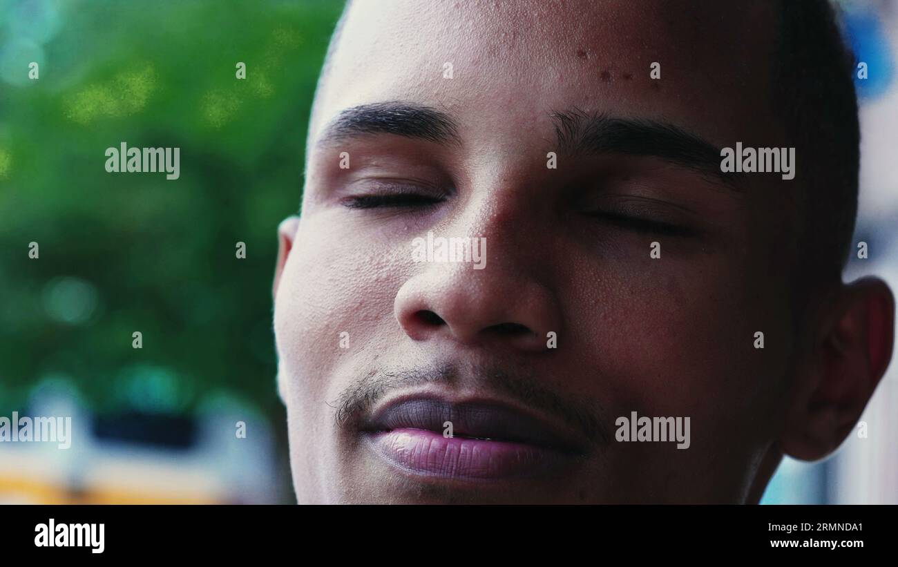 Religious Brazilian young man close-up face closing eyes and gazing upwards in Spiritual ...