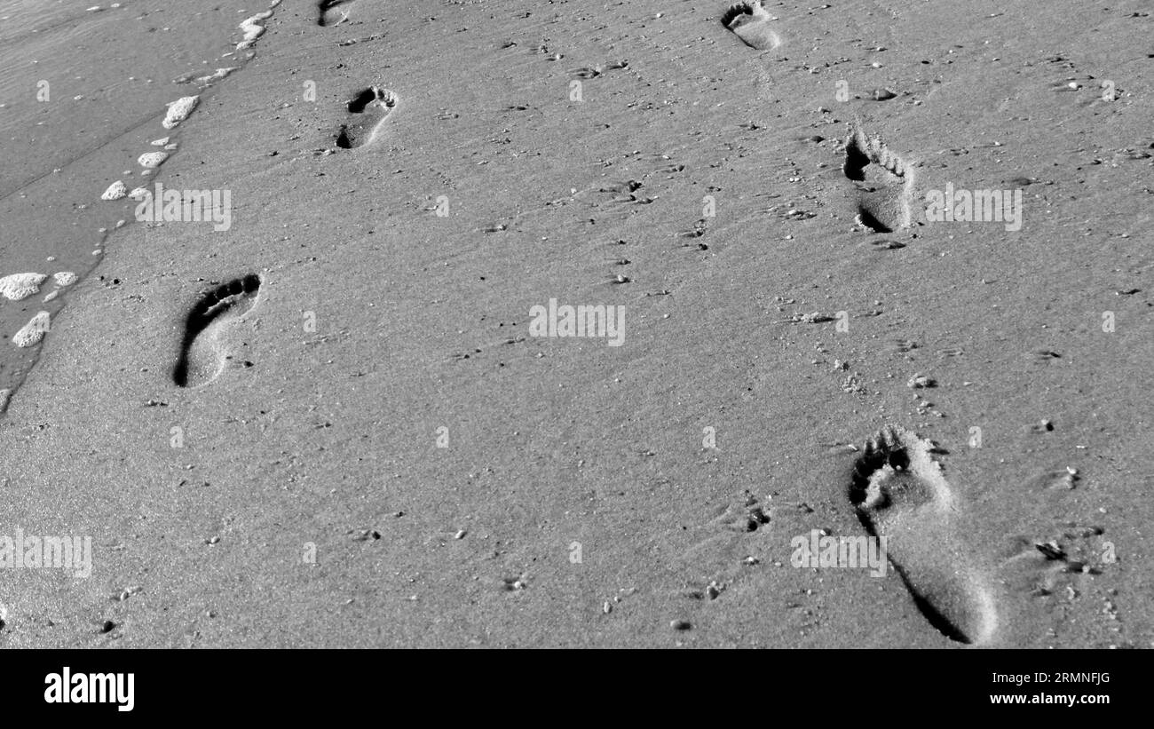 Following footprints on Beach Shore at Low Angle. Black and white scene ...
