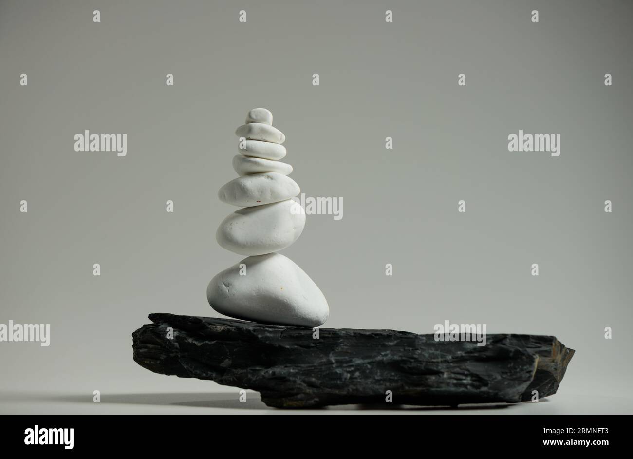 white smooth stones balanced over one black flat stone Stock Photo - Alamy