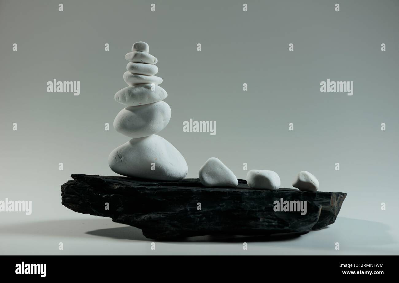 white smooth stones balanced over one black flat stone Stock Photo - Alamy
