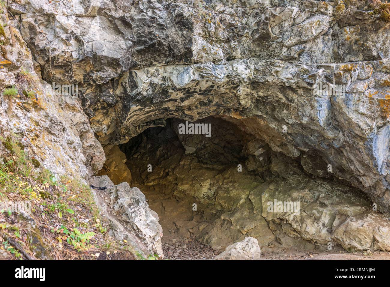 Limestone cliff wall with entrance of the cave. Cave in a layered ...