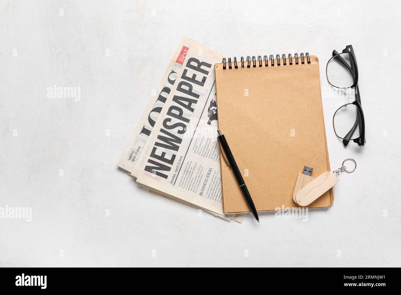 Notebook with USB flash drive, newspapers and eyeglasses on white ...